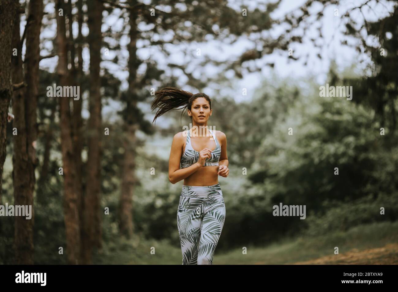 Pretty young fitness woman running at the forest trail Stock Photo - Alamy