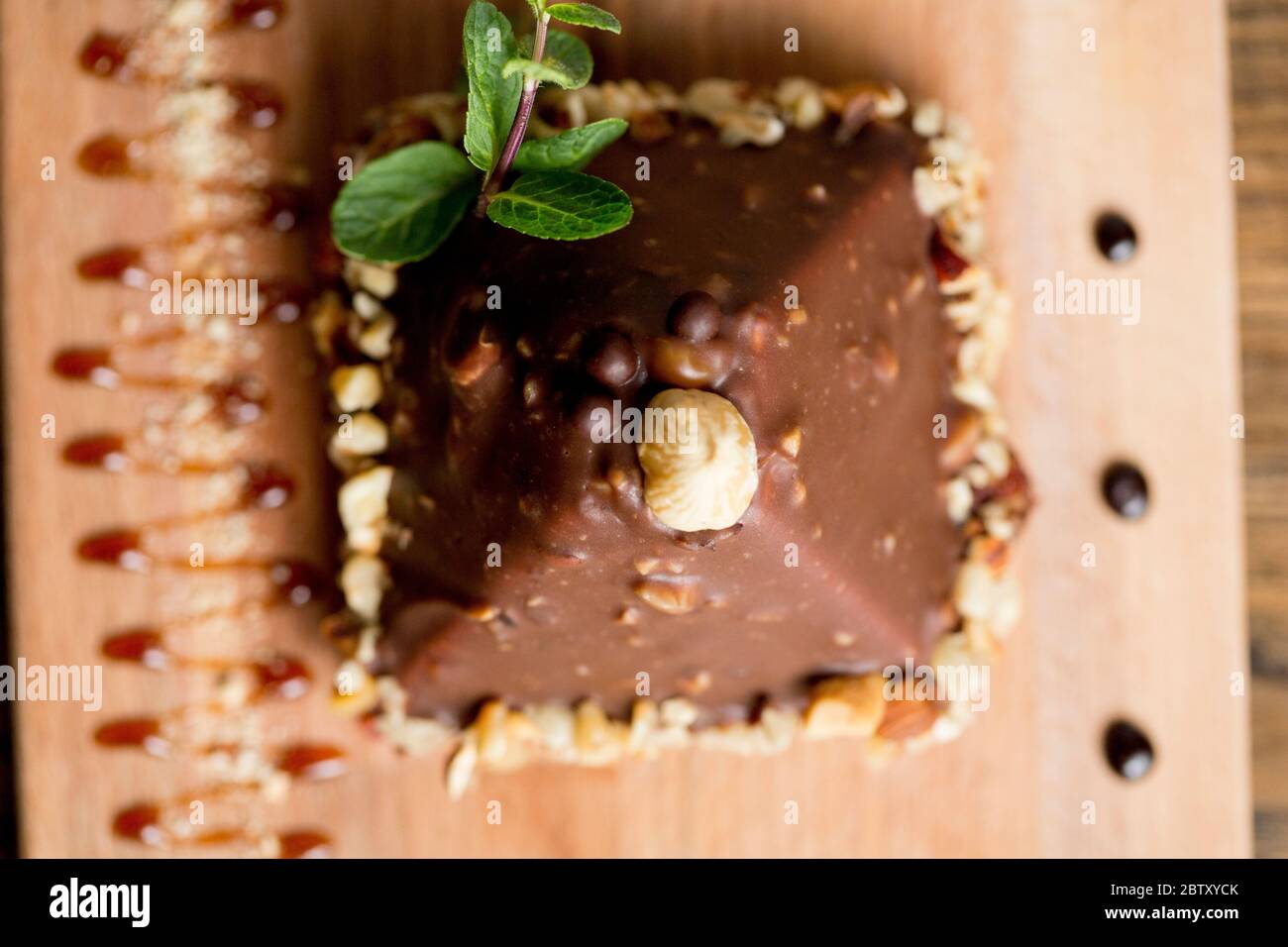 Chocolate pyramid shape cake with nuts on the wooden plate Stock Photo ...