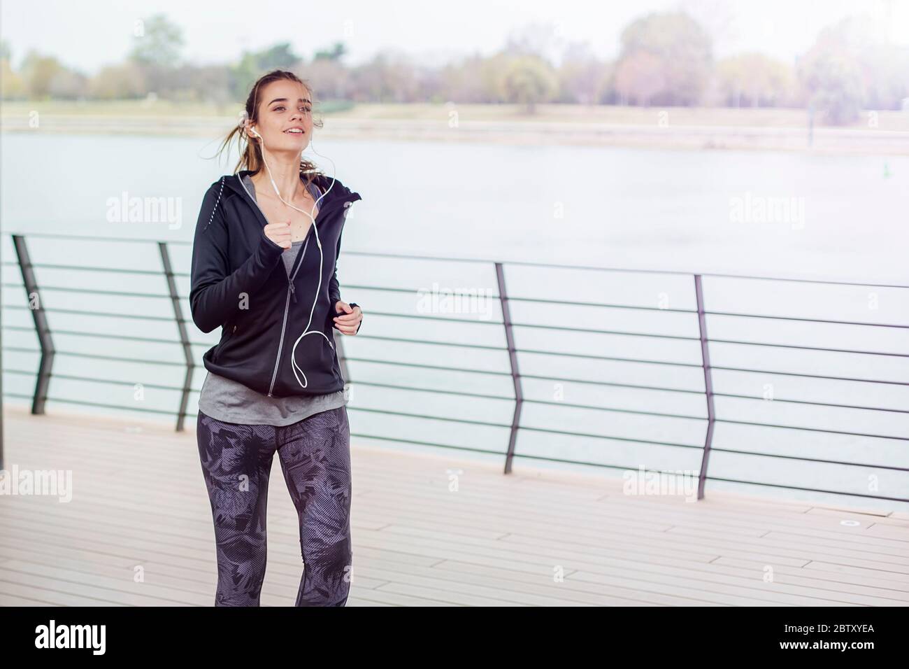 Healthy cute young woman running on the riverside promenade Stock Photo ...