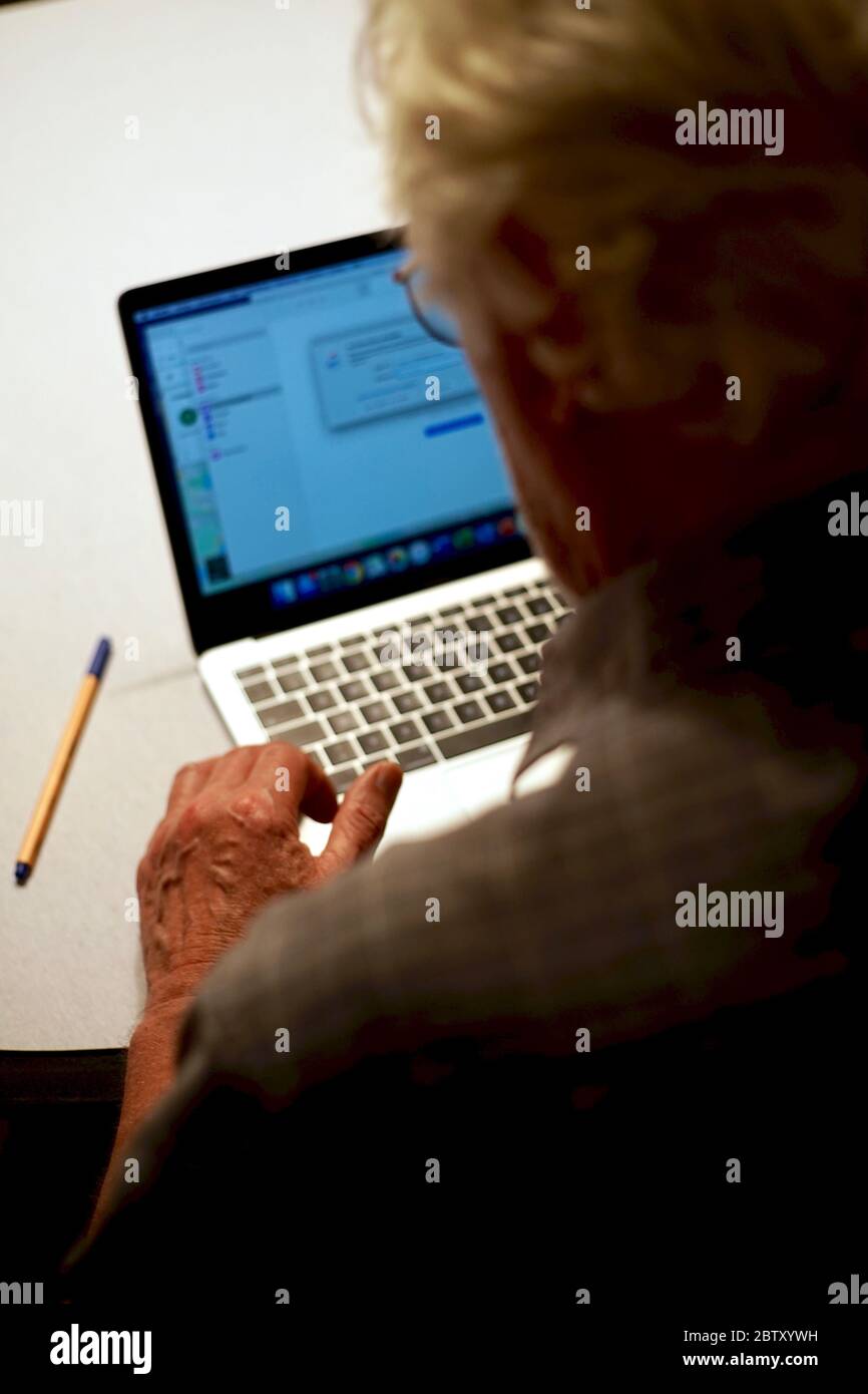 Over shoulder back view of white haired retired senior man using laptop ...