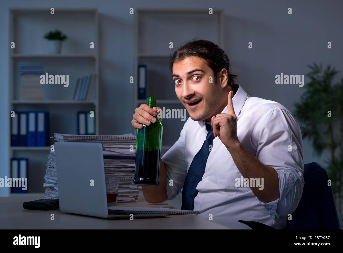 Alcohol addicted businessman working late Stock Photo - Alamy