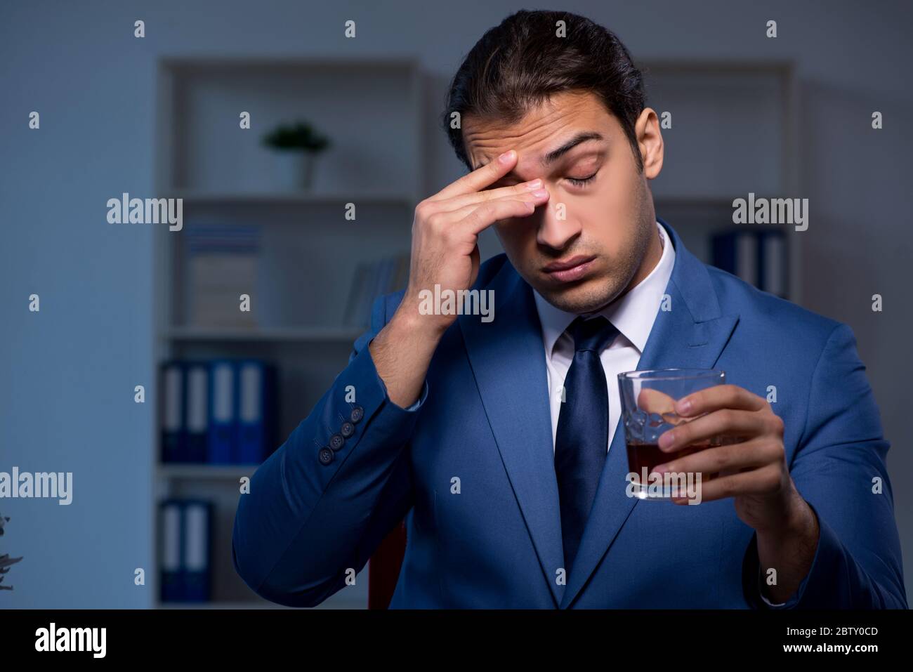 Alcohol addicted businessman working late Stock Photo - Alamy
