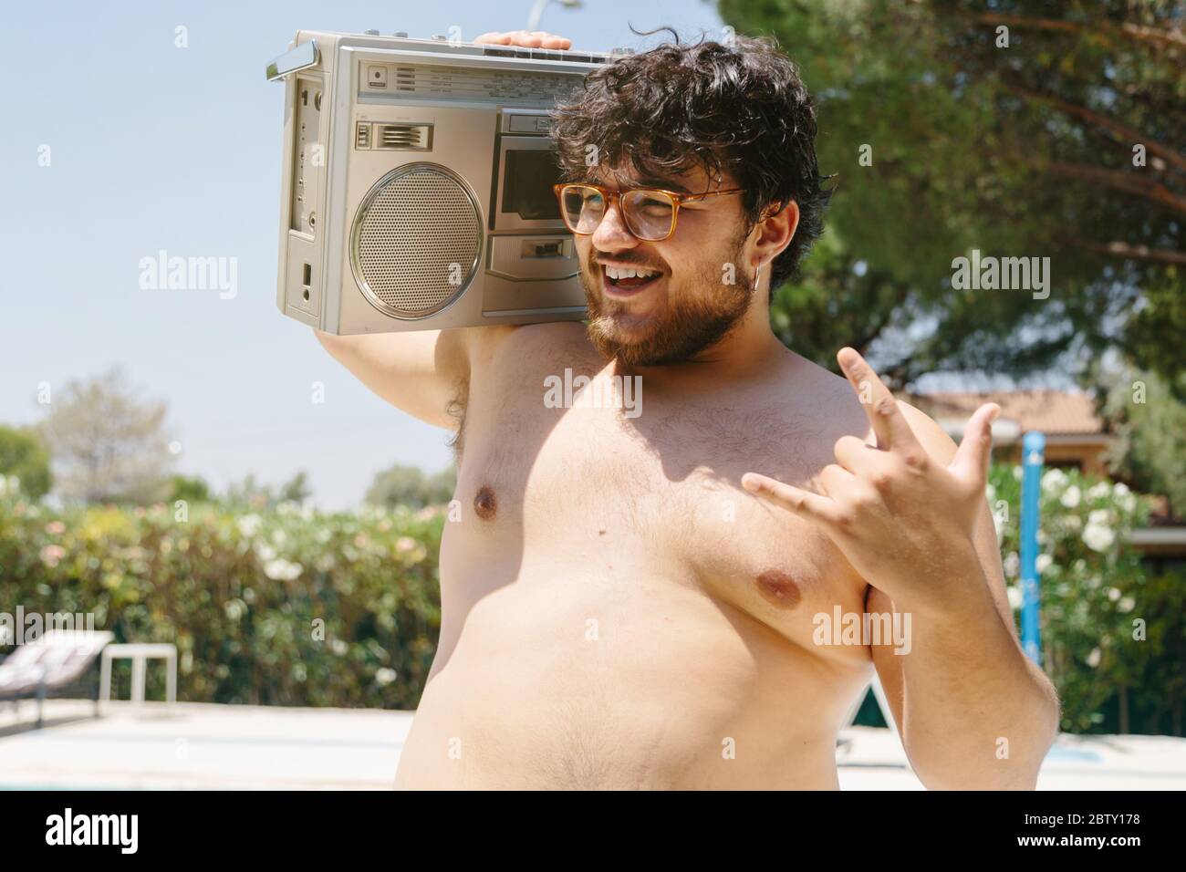 Young fat man with a pierced ear and glasses wearing a radio cassette ...