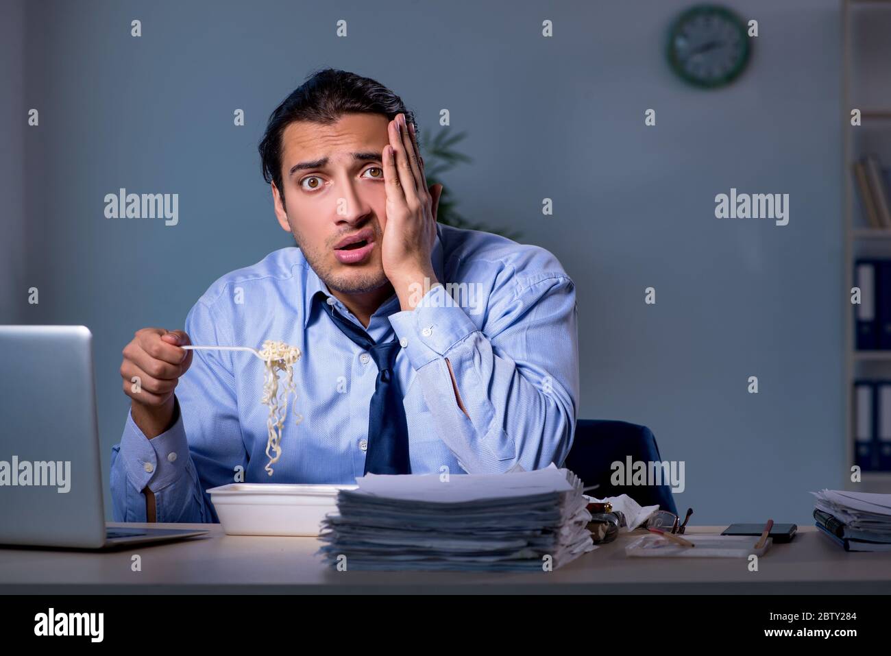 Hungry employee working late in office Stock Photo - Alamy