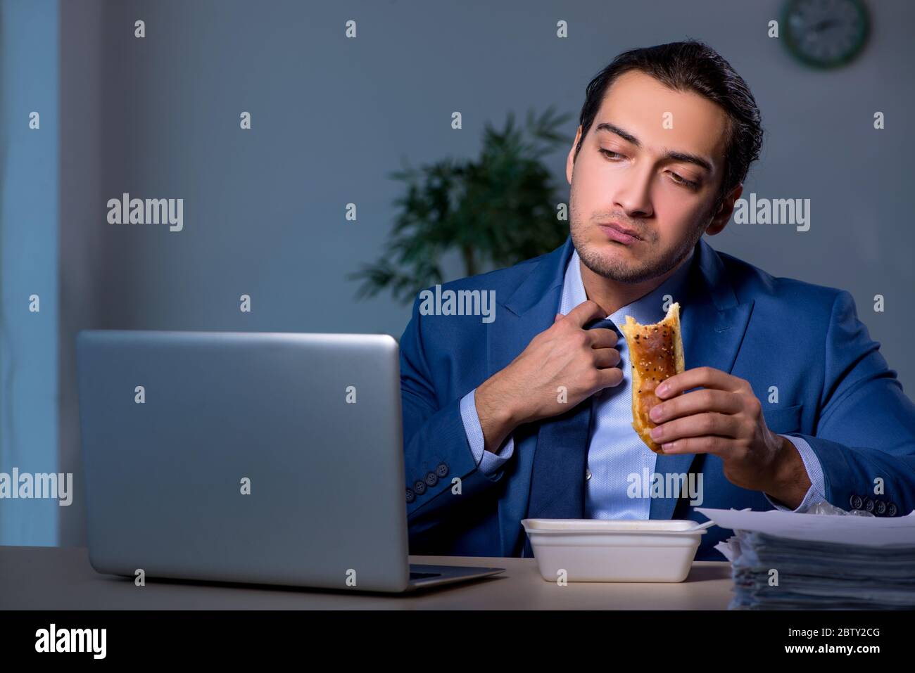 Hungry employee working late in office Stock Photo - Alamy