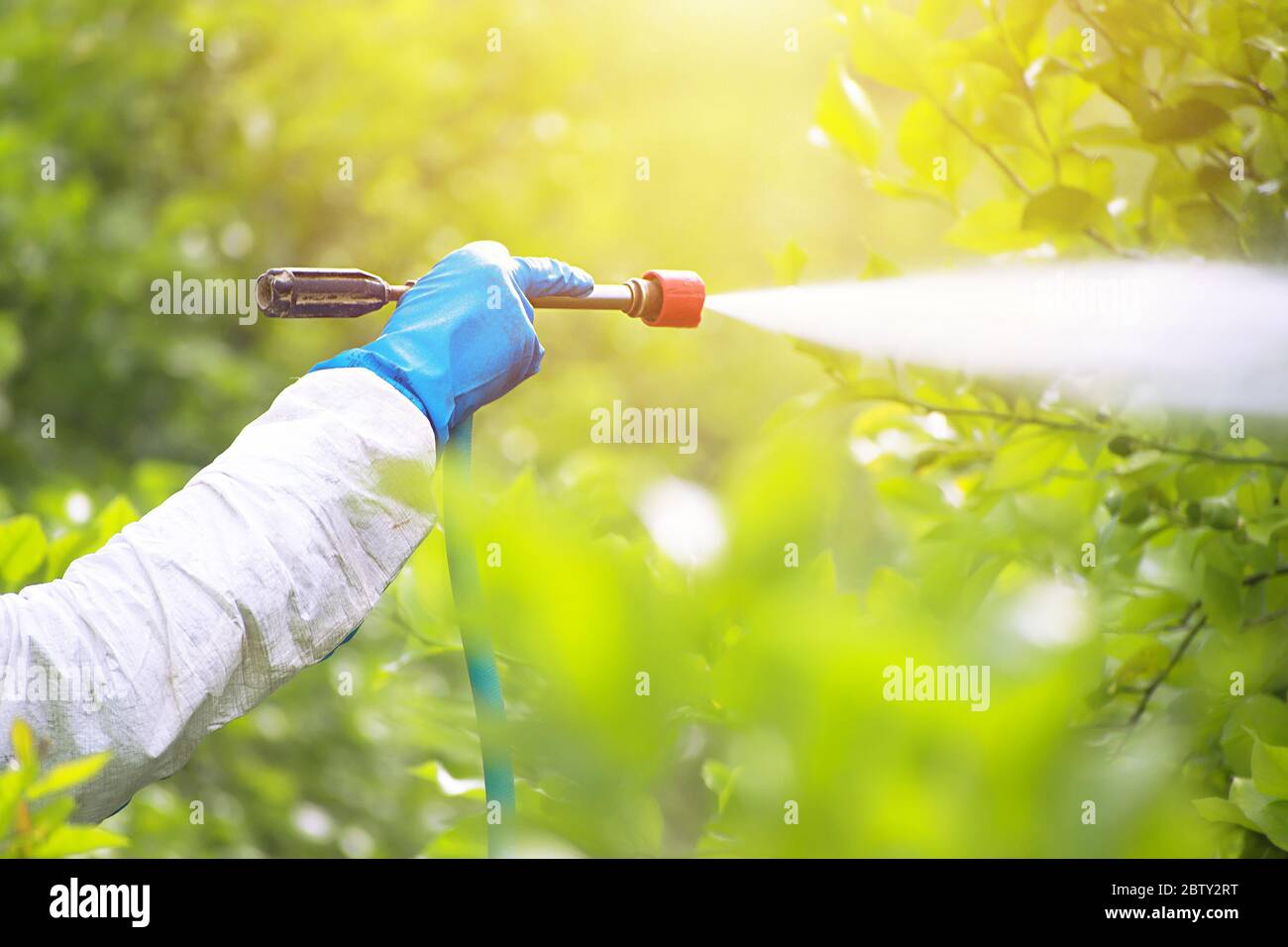Spray ecological pesticide. Farmer fumigate in protective suit and mask ...