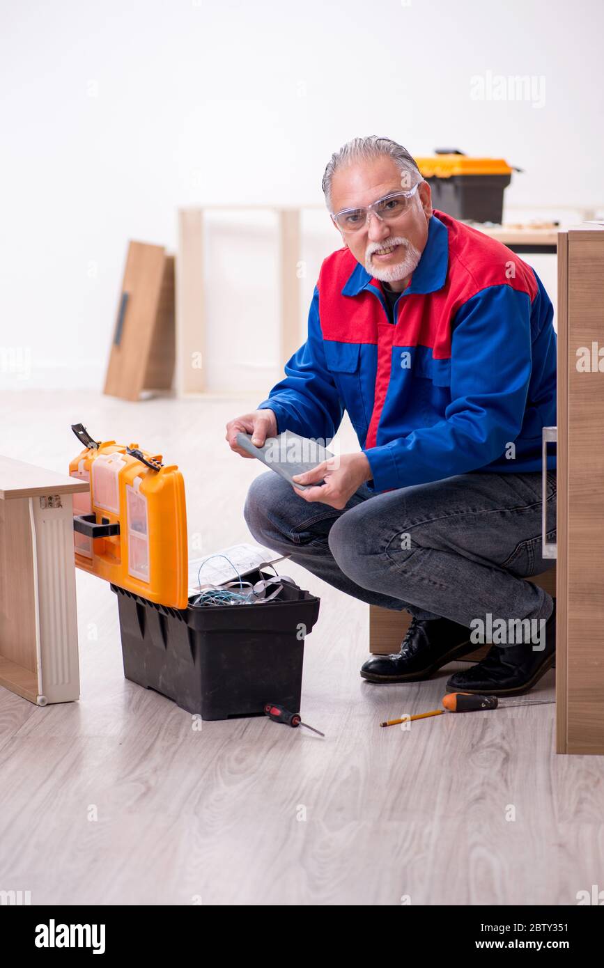 Old carpenter working indoors on furniture Stock Photo - Alamy