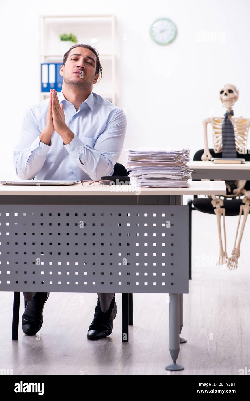 Young employee and skeleton in the office Stock Photo - Alamy