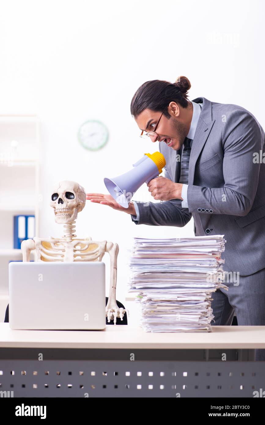 Young employee and skeleton in the office Stock Photo - Alamy