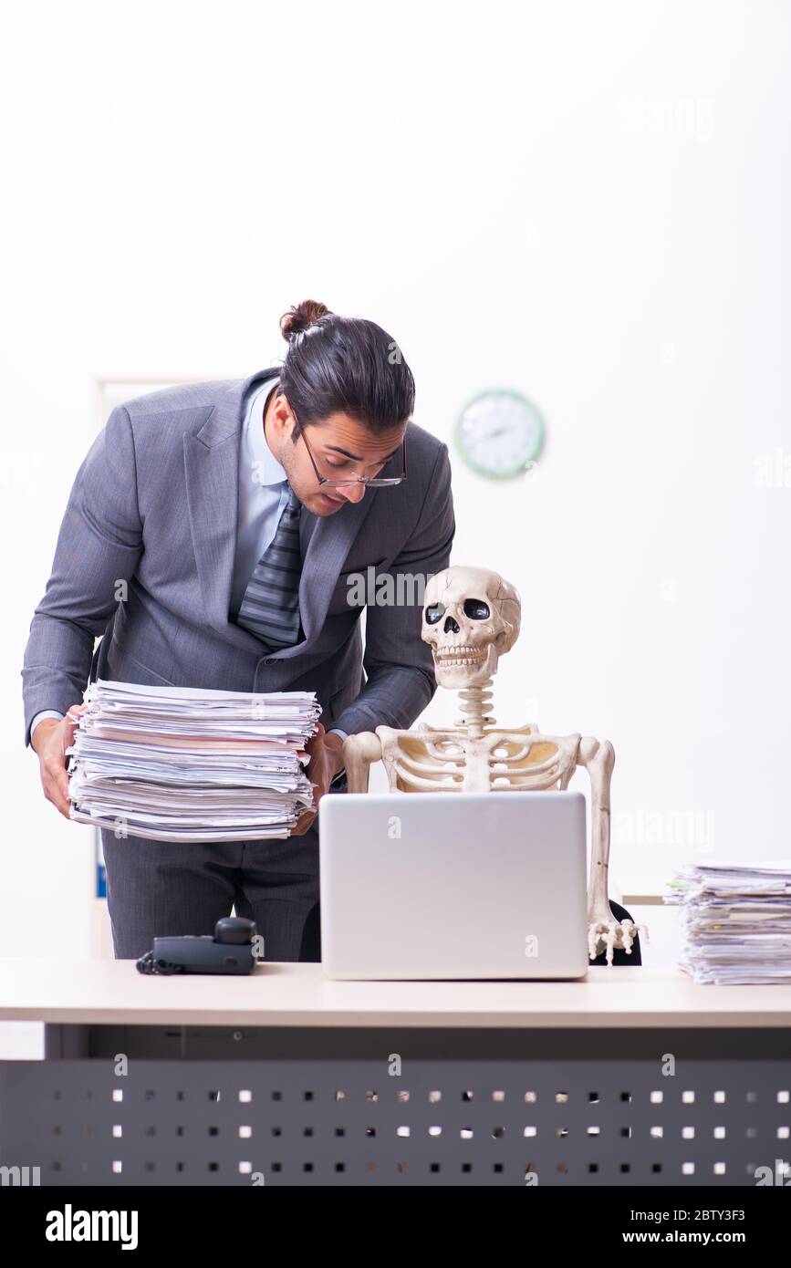 Young employee and skeleton in the office Stock Photo - Alamy