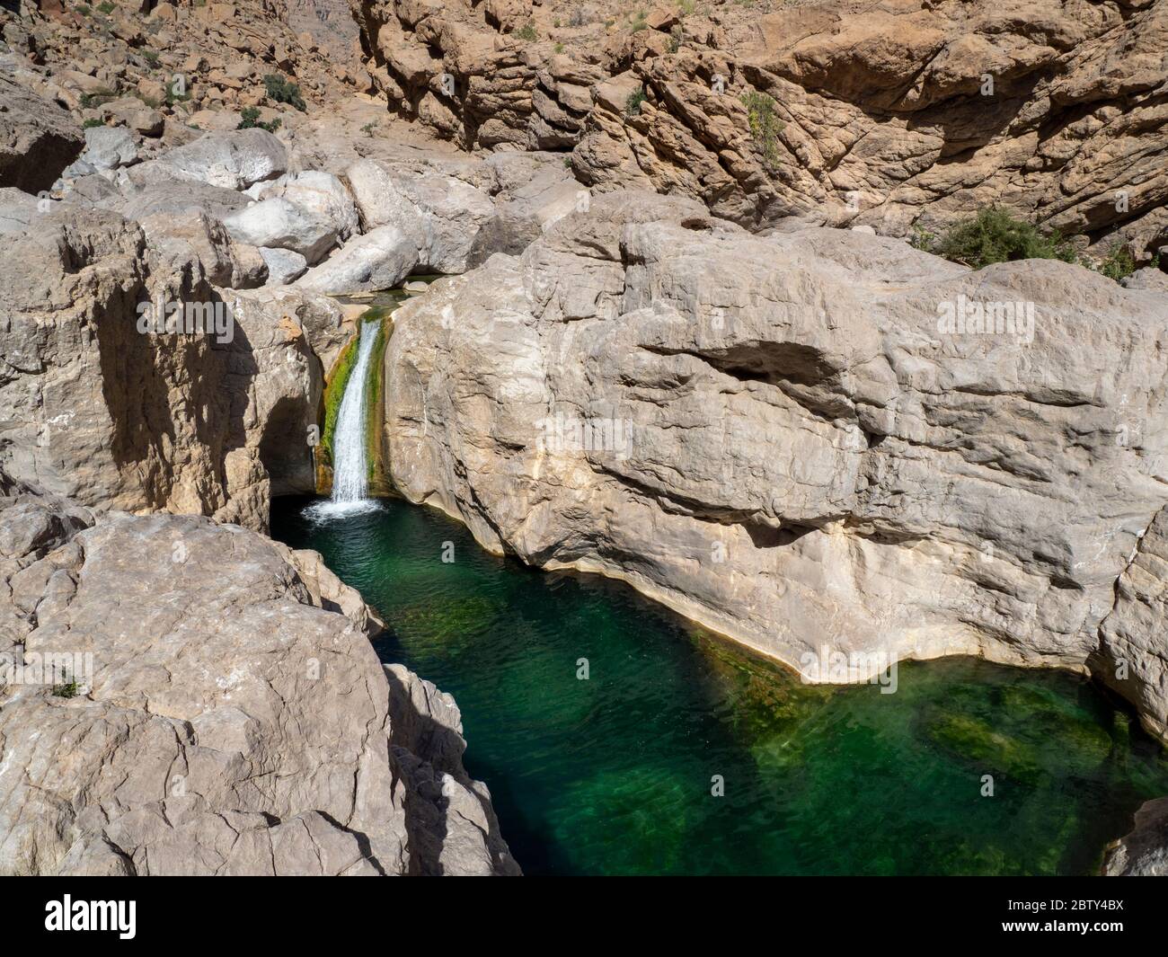 Waterfall dropping in to naturally formed swimming pools in Wadi Bani ...