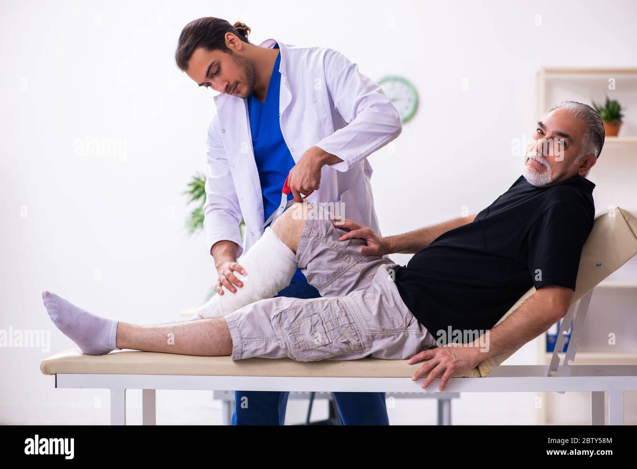 Old injured man visiting young doctor traumatologist Stock Photo - Alamy