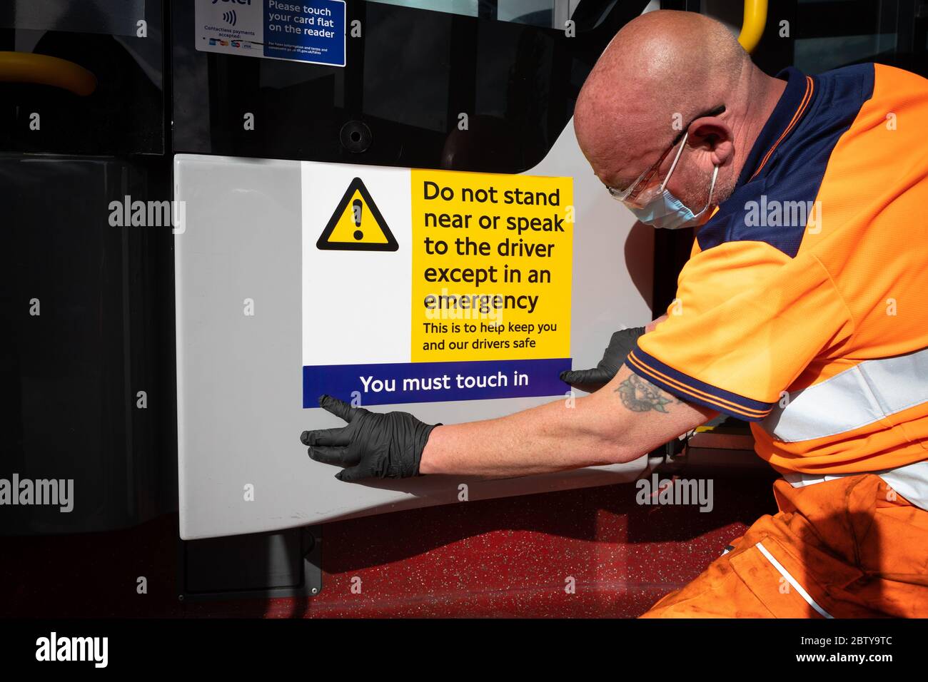Bus staff install stickers on a bus in Twickenham bus garage to remind ...