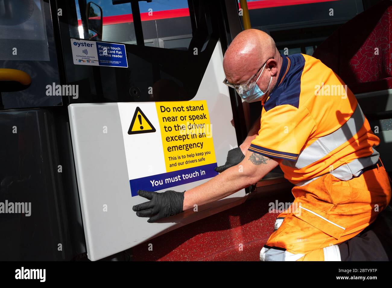 Bus staff install stickers on a bus in Twickenham bus garage to remind ...