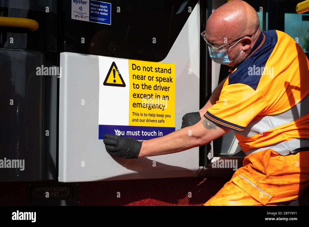 Bus staff install stickers on a bus in Twickenham bus garage to remind ...