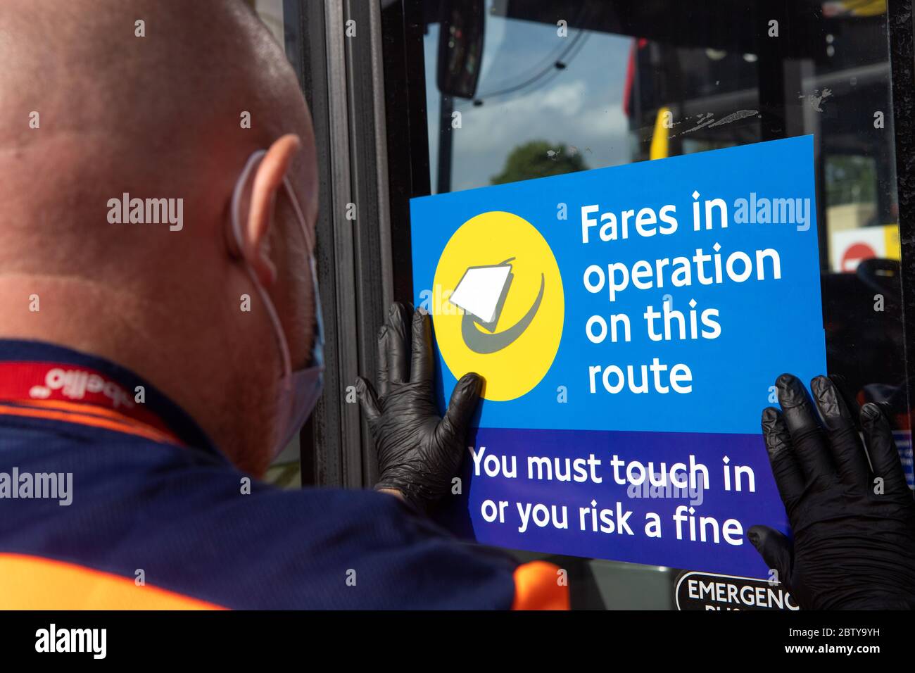 Bus staff install stickers on a bus in Twickenham bus garage to remind ...