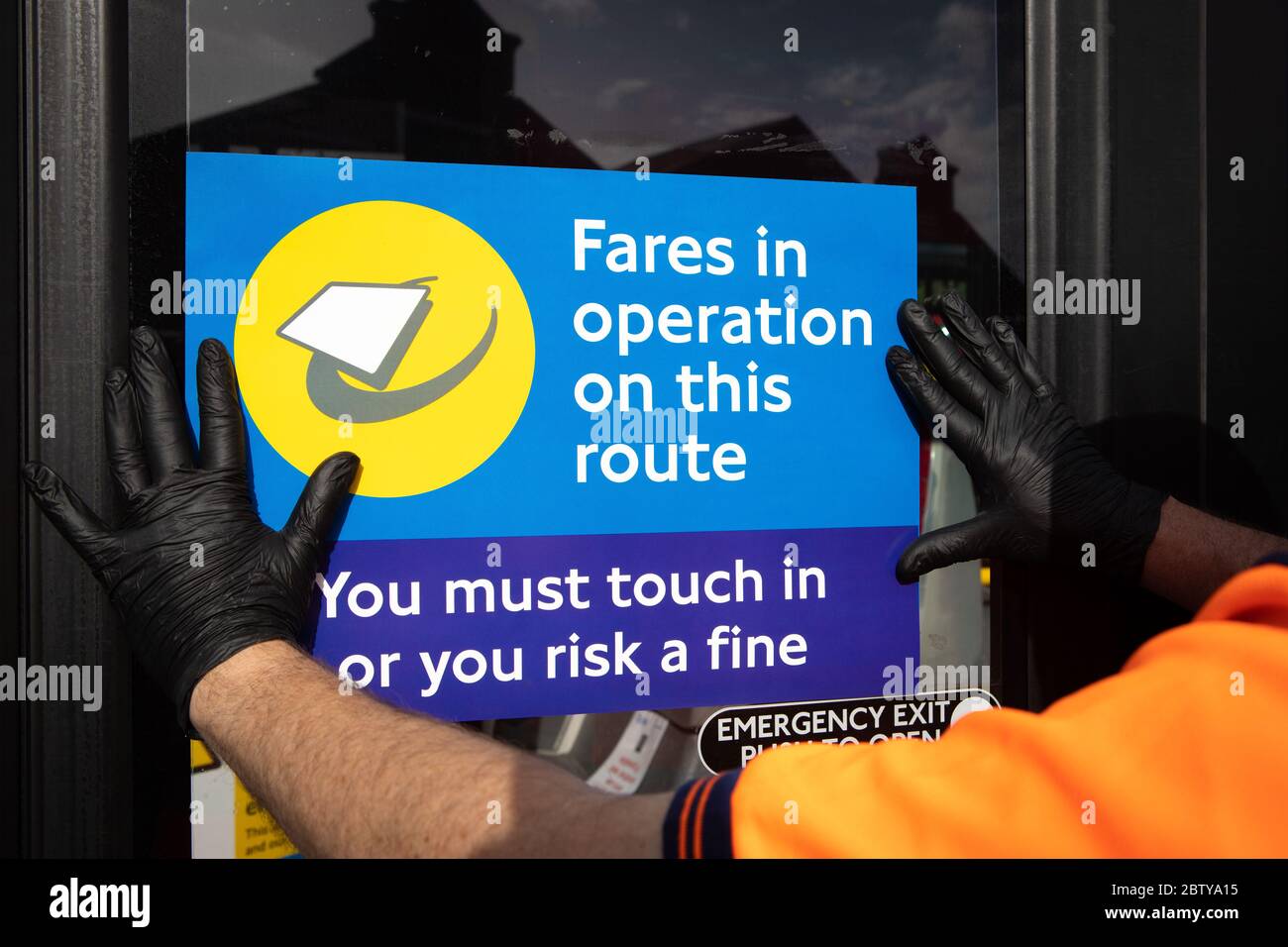 Bus staff install stickers on a bus in Twickenham bus garage to remind ...