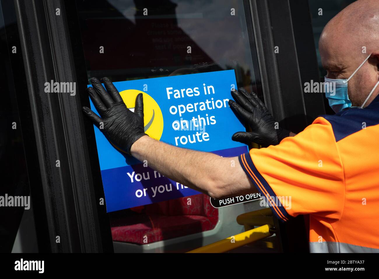 Bus staff install stickers on a bus in Twickenham bus garage to remind ...