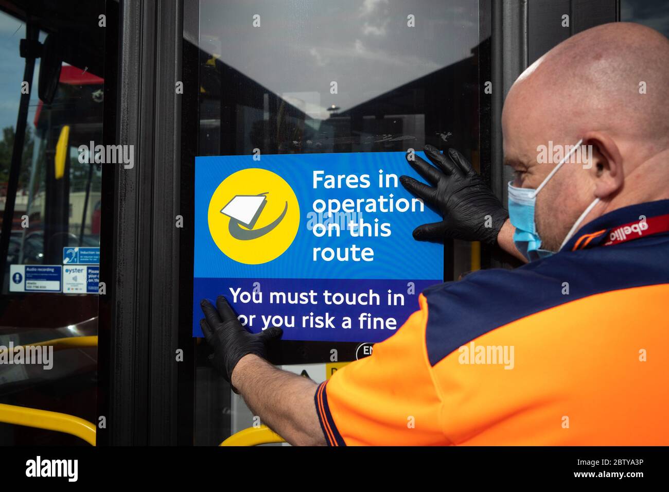 Bus staff install stickers on a bus in Twickenham bus garage to remind ...