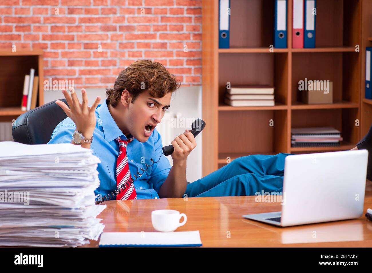 The young employee with excessive work sitting at the office Stock ...
