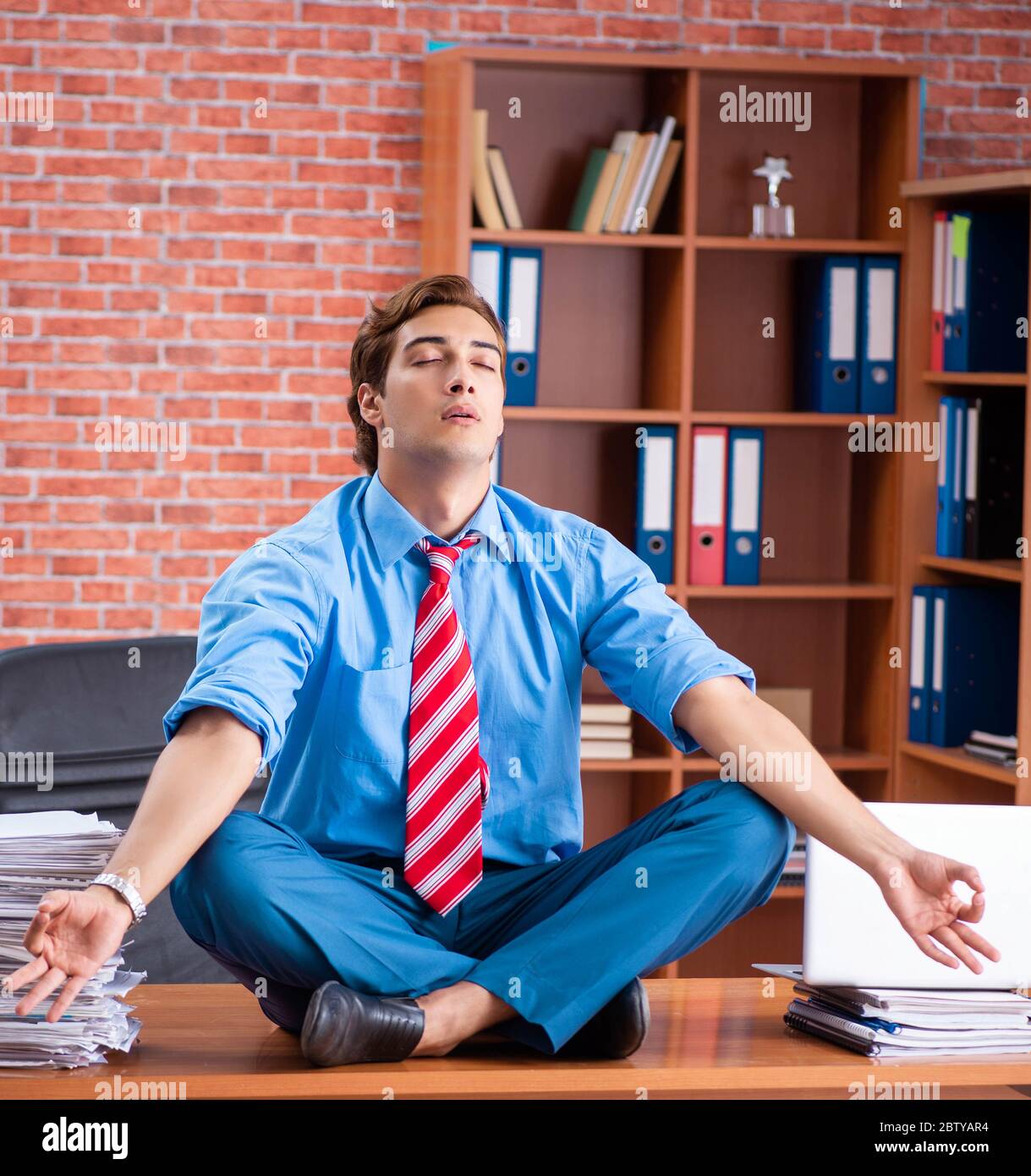 The young employee with excessive work sitting at the office Stock ...