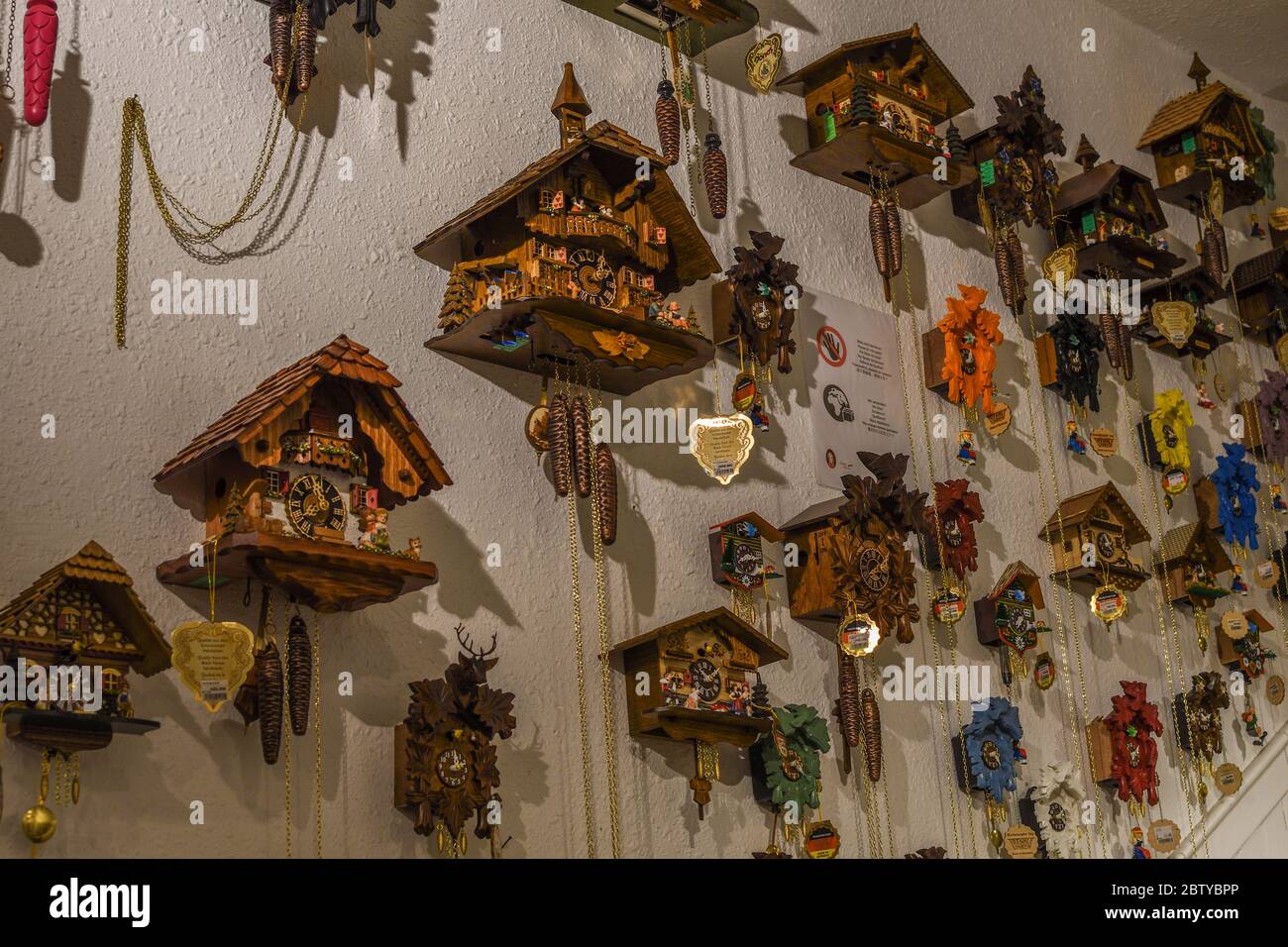 Many wooden classic carved clocks hanging on the wall, in the store ...