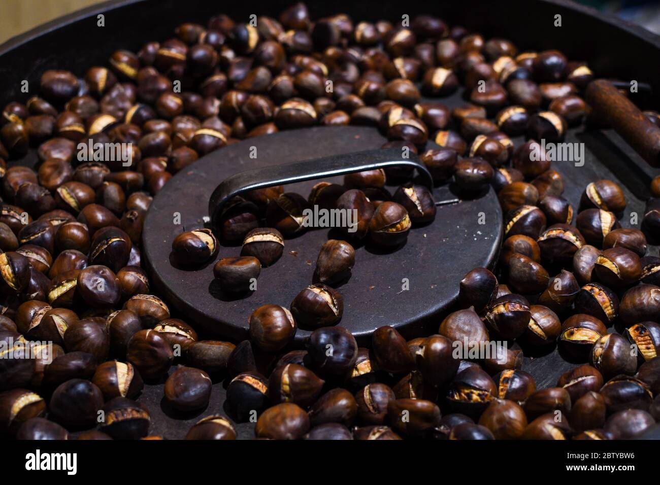 Frying chestnuts being prepared cooking in a large pot over the fire ...