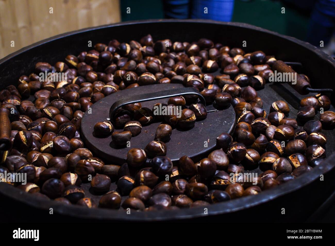 Frying chestnuts being prepared cooking in a large pot over the fire ...