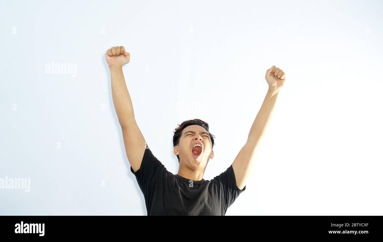 Successful casual asian man raising arms after winning something Stock ...