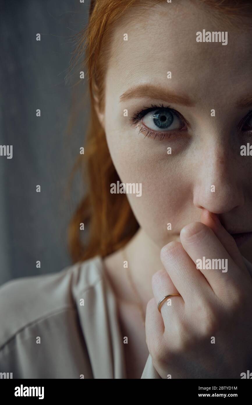 Close shot of half face of red-haired girl with blue eyes. A look into ...