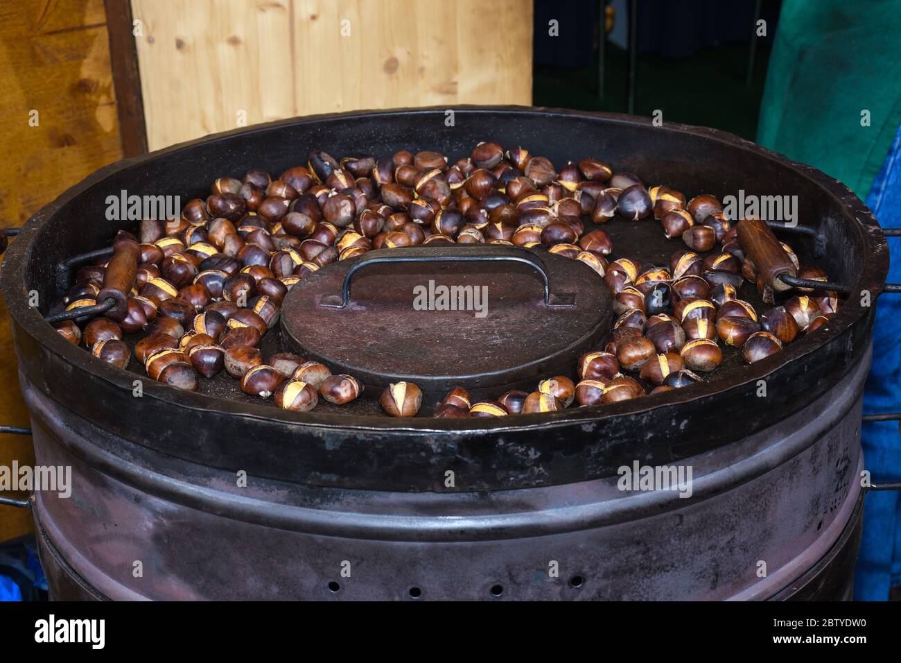 Frying chestnuts being prepared cooking in a large pot over the fire ...