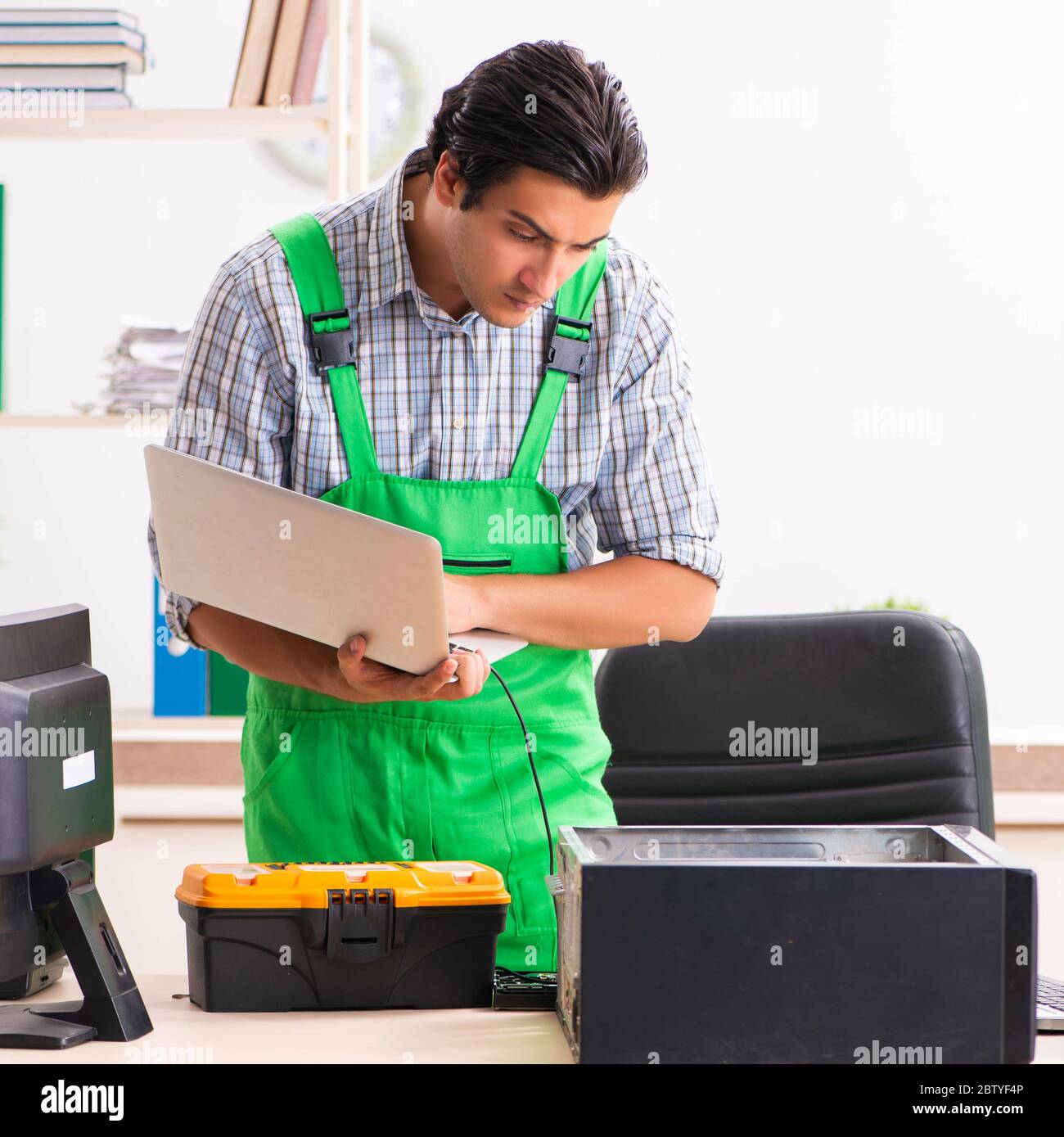 The young engineer repairing broken computer at the office Stock Photo ...