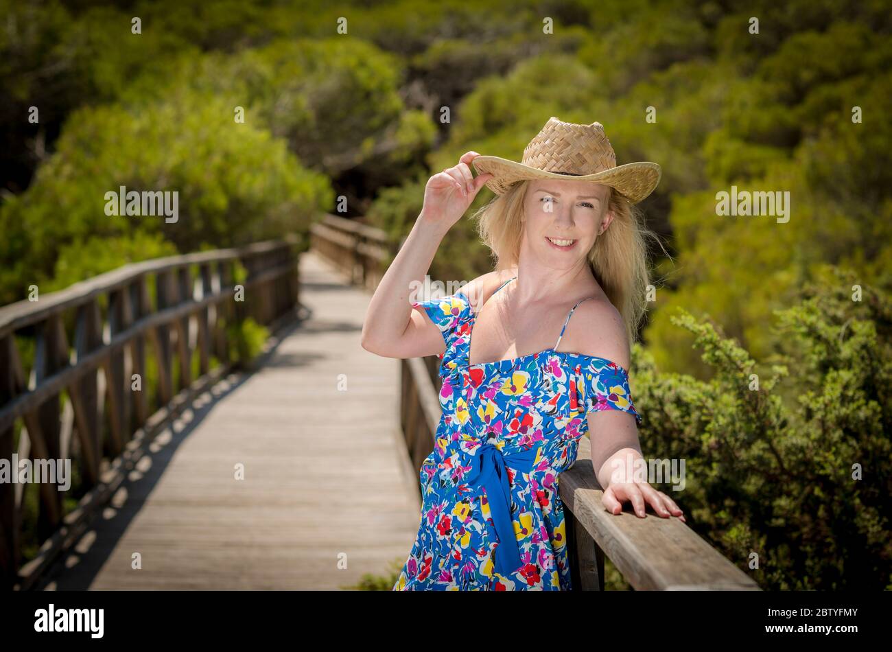 Pretty young woman wearing a colourful sundress and sunhat in Mallorca ...