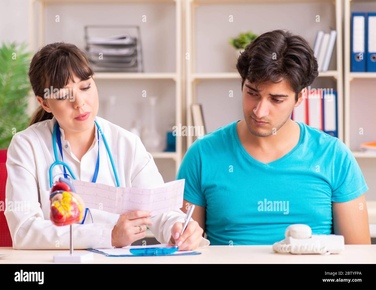 The young man visiting female doctor cardiologist Stock Photo - Alamy