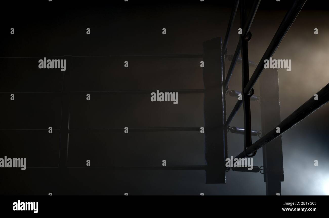 A dramatic closeup of a dimly spotlit corner of a boxing ring ...