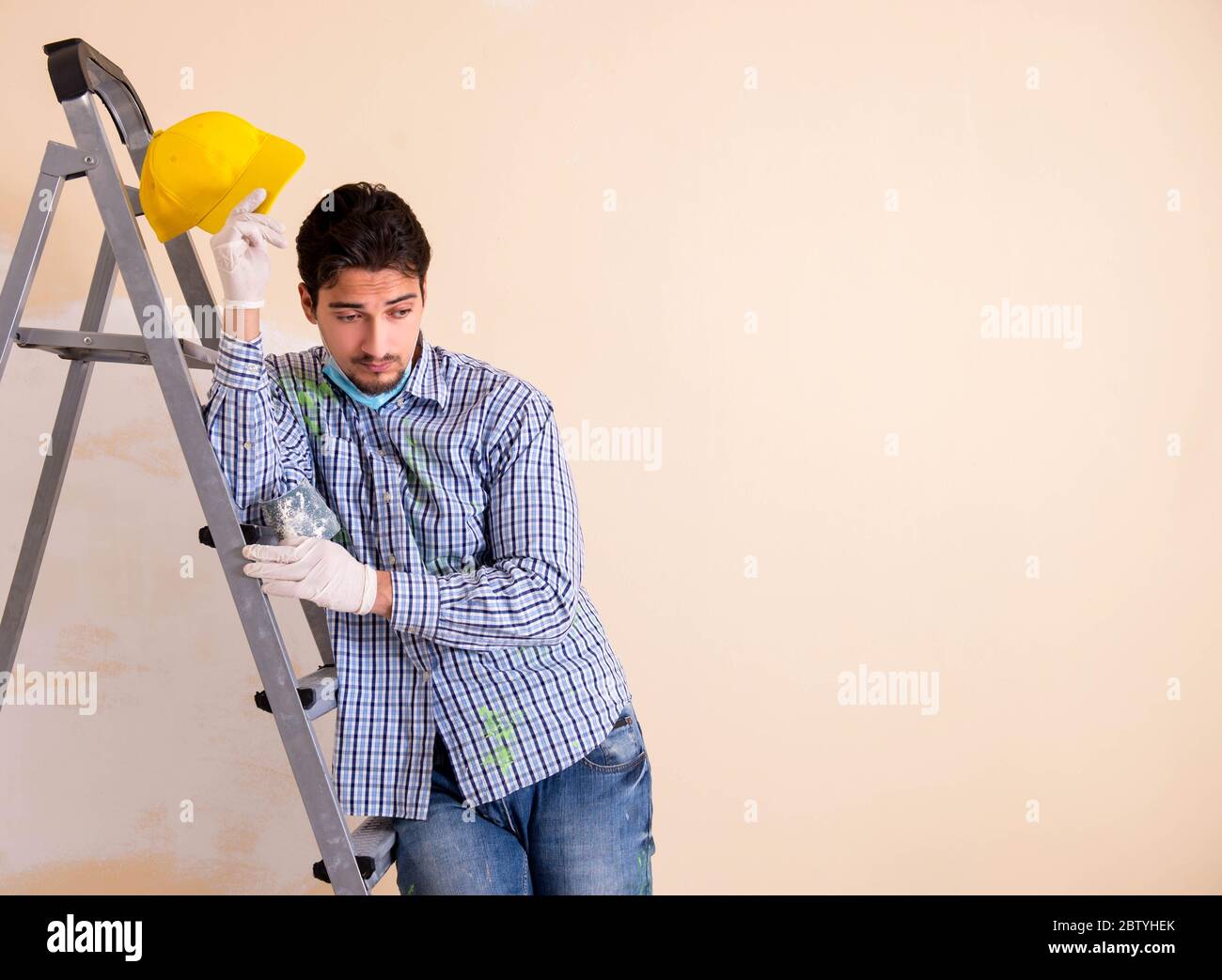 The young contractor sanding wall down with sandpaper Stock Photo - Alamy