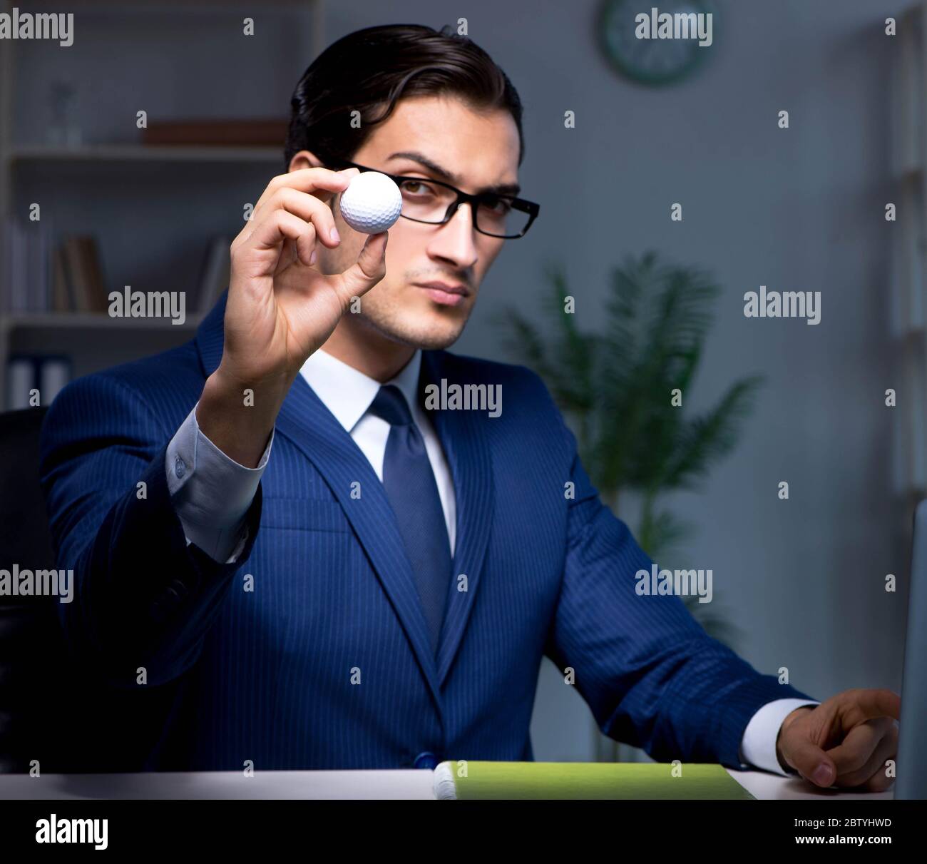 The young employee with golf ball in office Stock Photo - Alamy