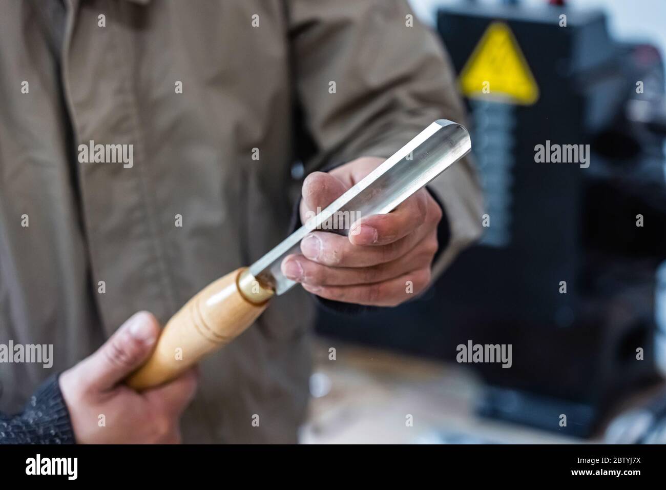 Man is holding the chisel for woodwork. Worker is keeping the new metal ...