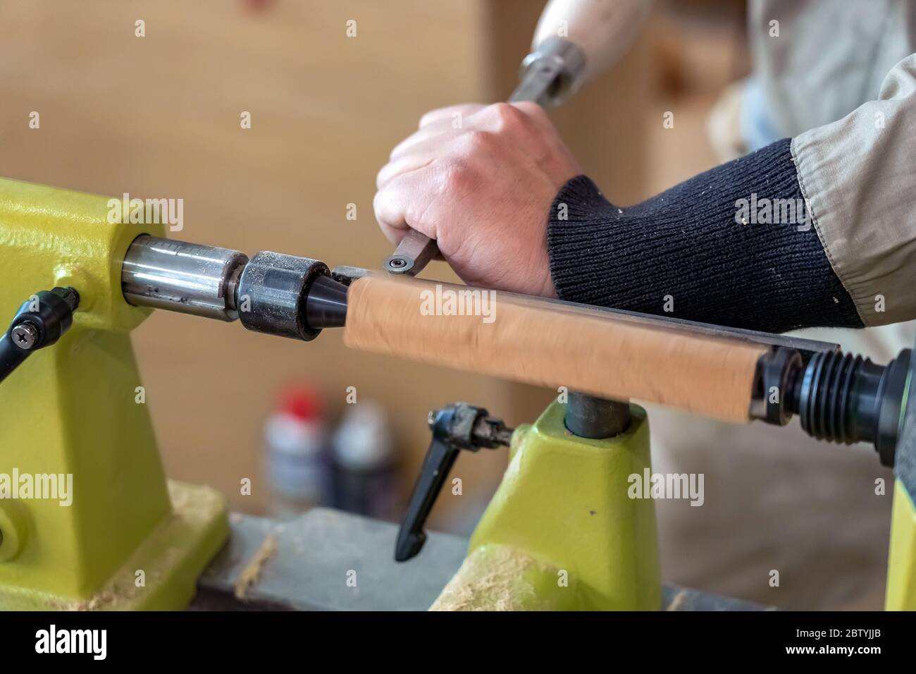 Carpenter man is carving the wooden stick. Spinning wood wheel machine ...