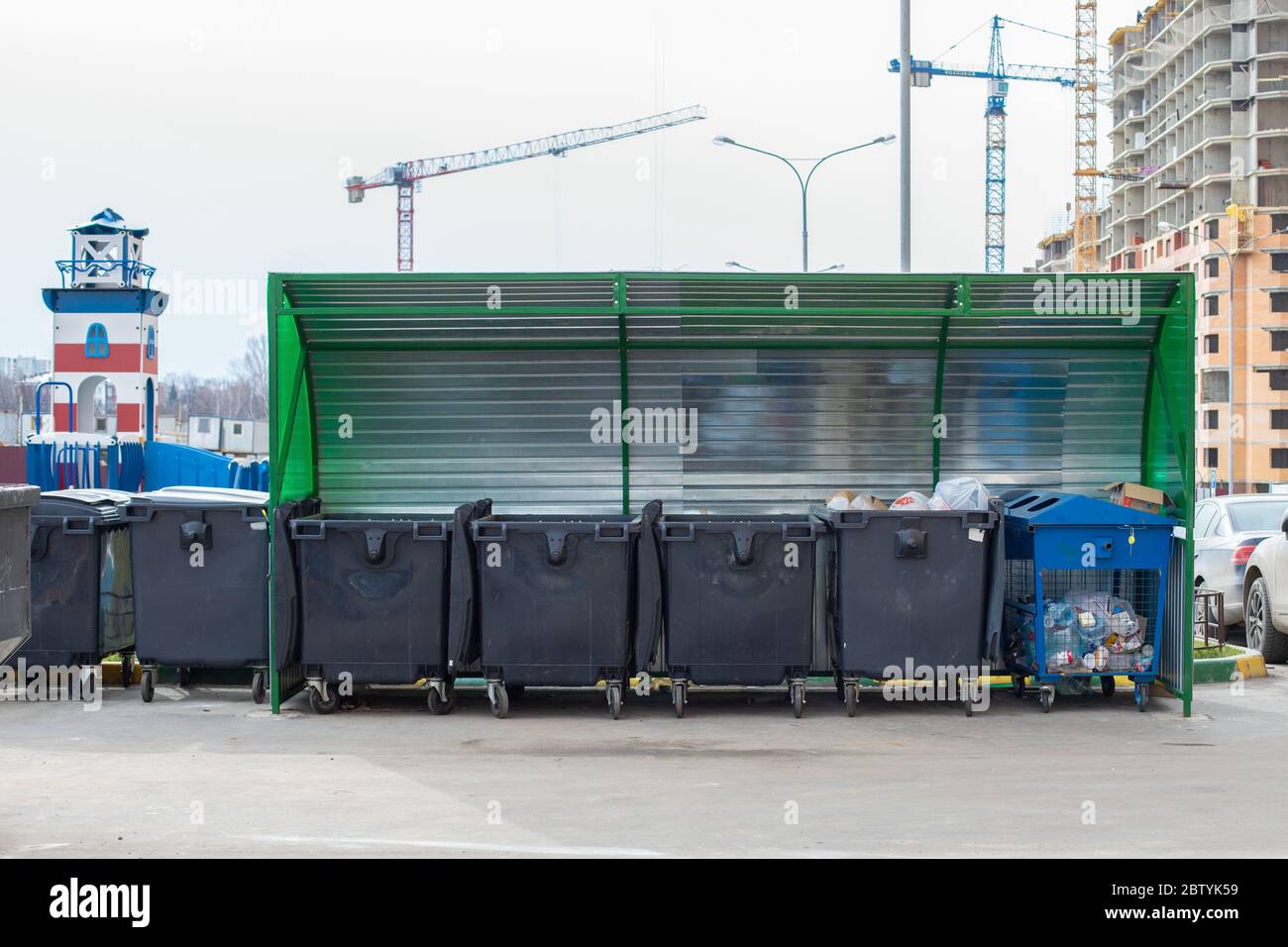 Lots of black plastic trash containers, residential area new building ...