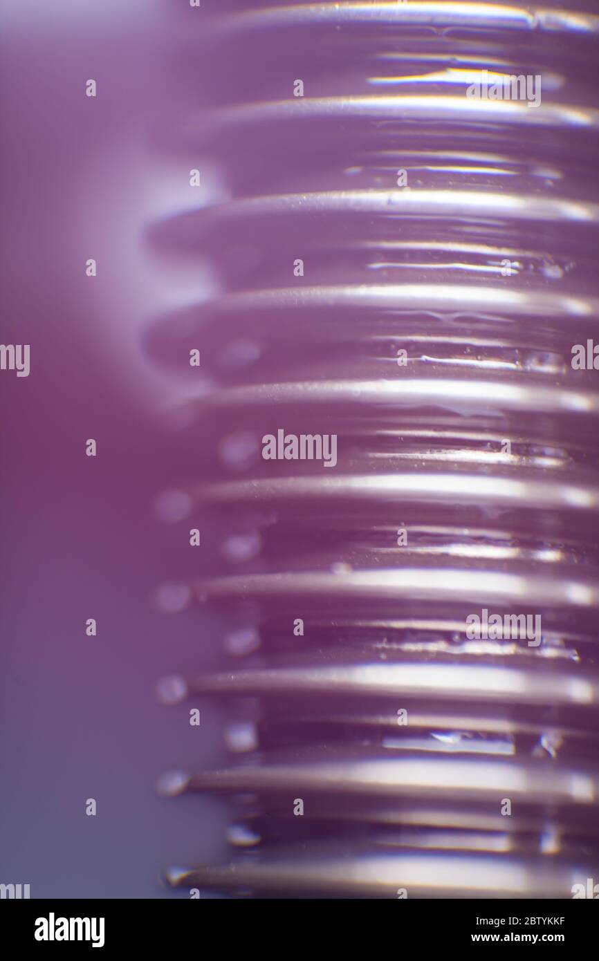 Close-up of a screw bolt in lilac and purple on a dark background ...