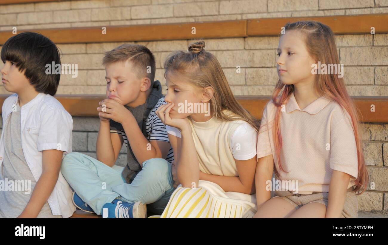 Tired and exhausted primary school kids sitting outdoors Stock Photo ... Tired and exhausted primary school kids sitting outdoors Stock Photo ...