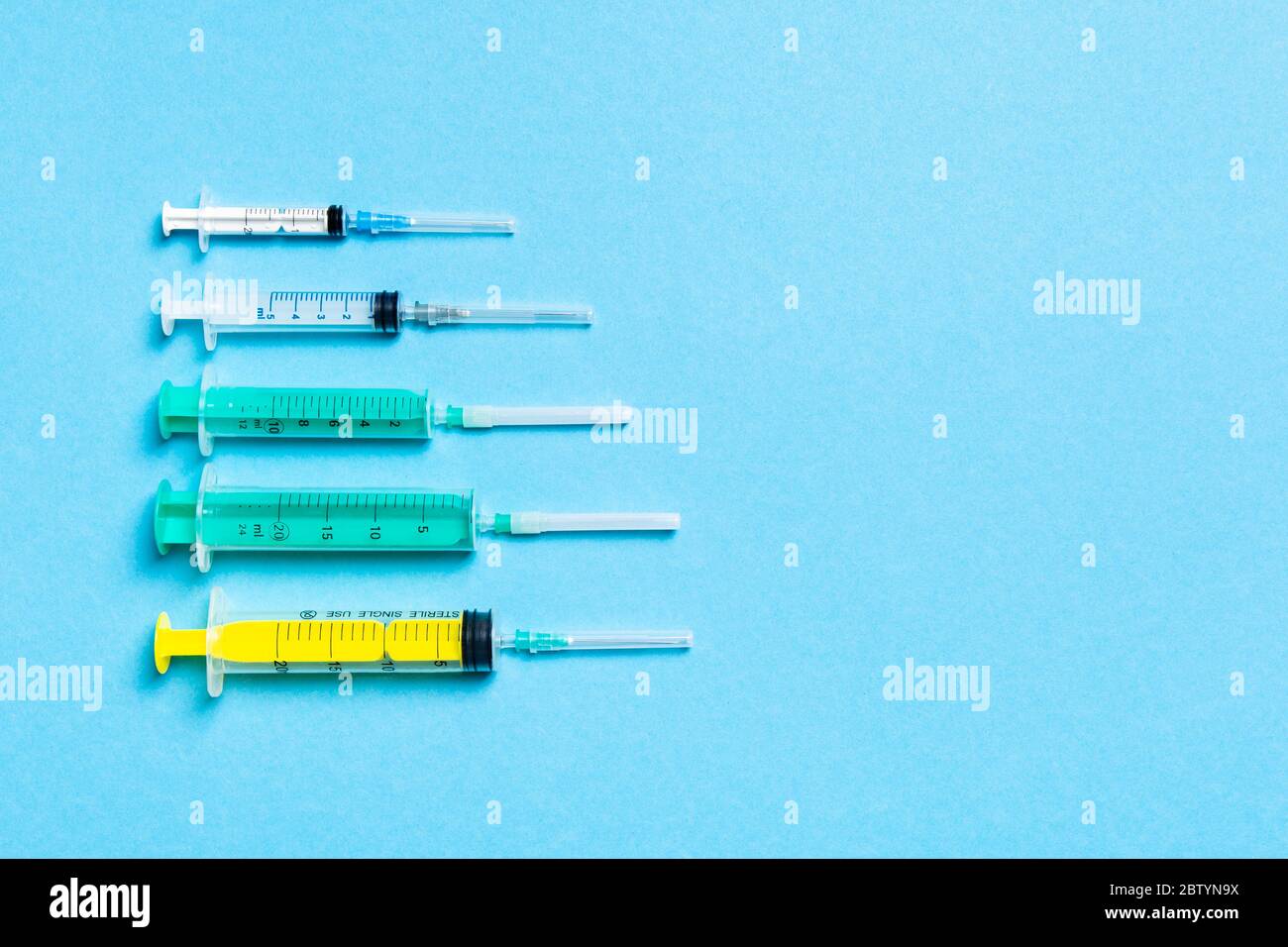 Top view of medical syringes with needles at blue background with copy ...