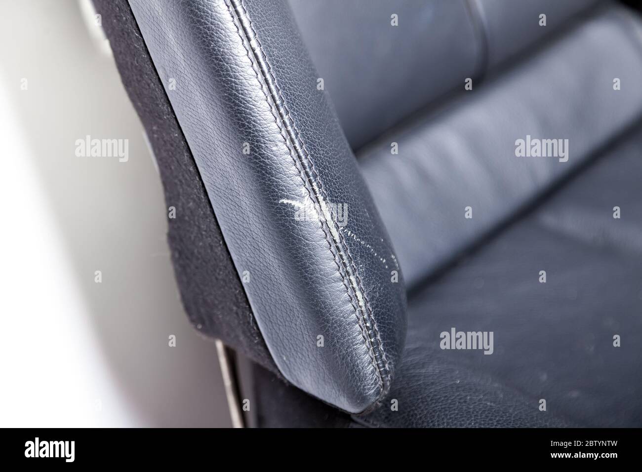Closeup of a defect on a black leather car armchair - white dash of ...