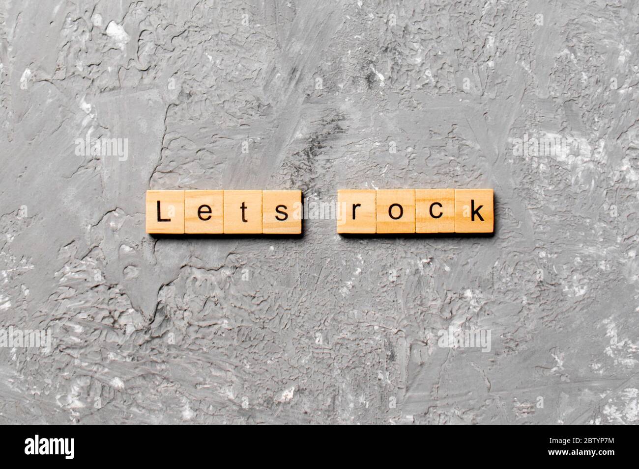 Let's Rock word written on wood block. Lets Rock text on cement table ...