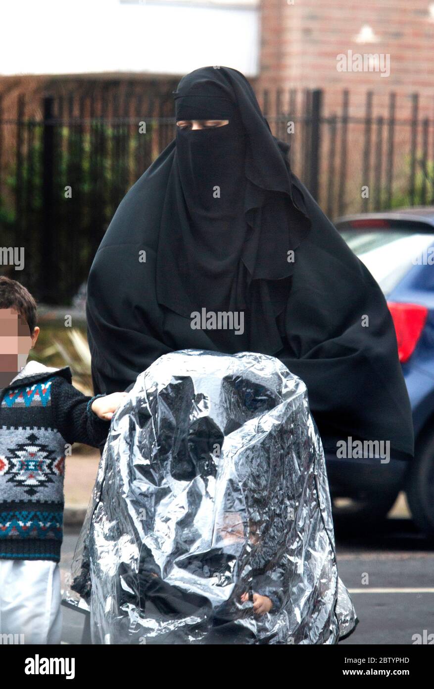A woman walks on a British street wearing a Burka face covering ...