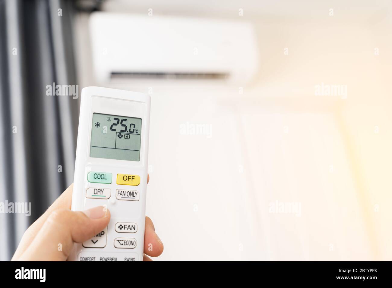 Human hand is using white remote of air conditioner for turn on or ...