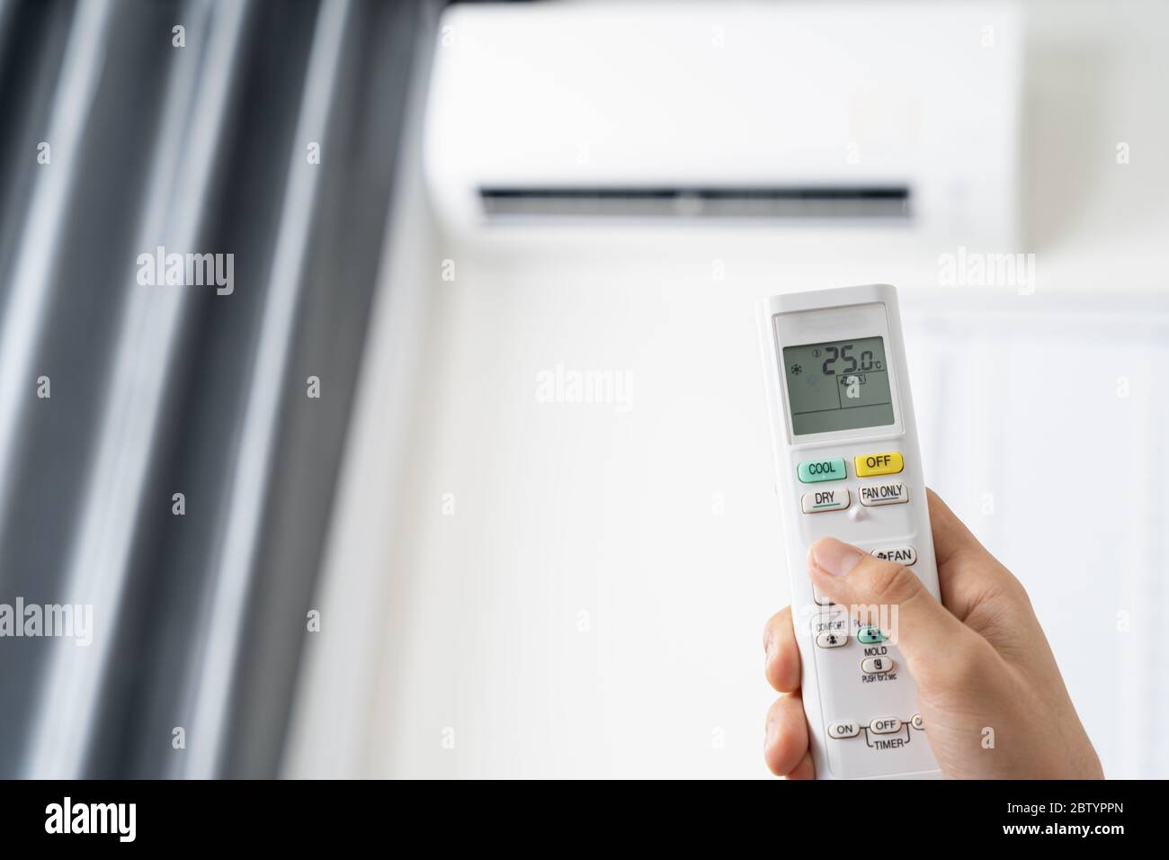 Human hand is using white remote of air conditioner for turn on or ...