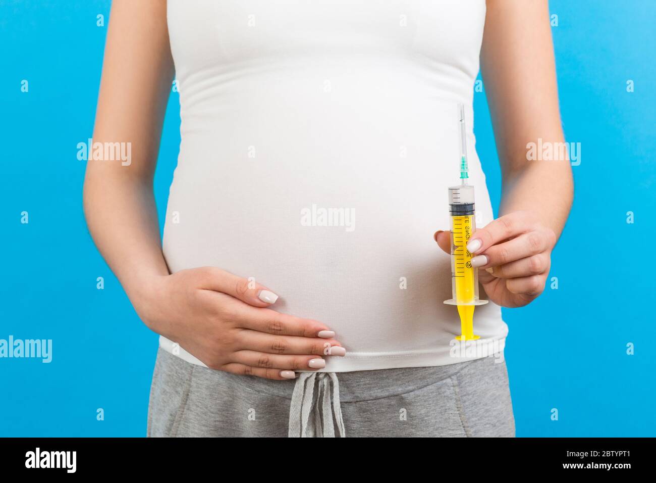 Close up of syringe for injection in pregnant woman's hand at colorful ...