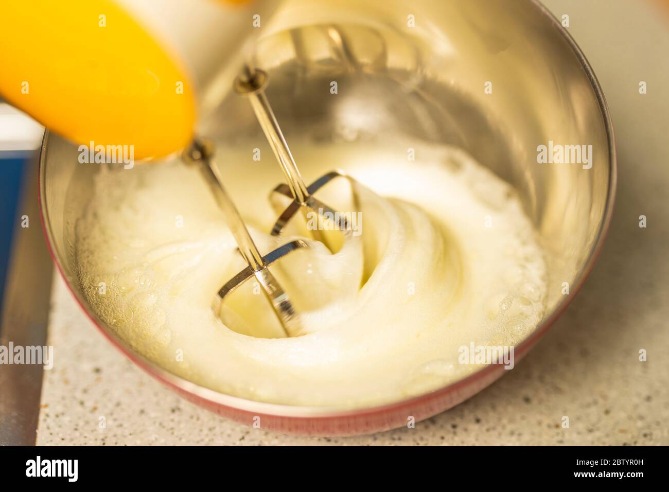 Beating a white cream with a mixer in a metal bowl. Whipped cream ...